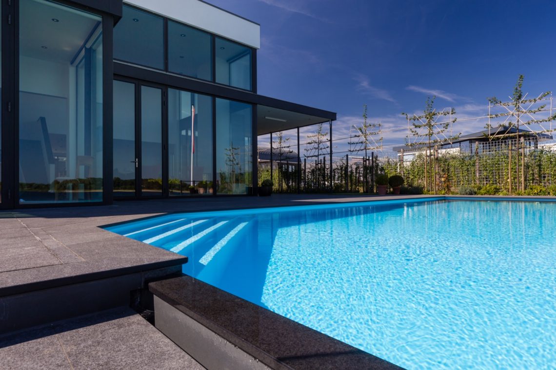 Infinity pool with overflow channel and natural stone bench seating ...